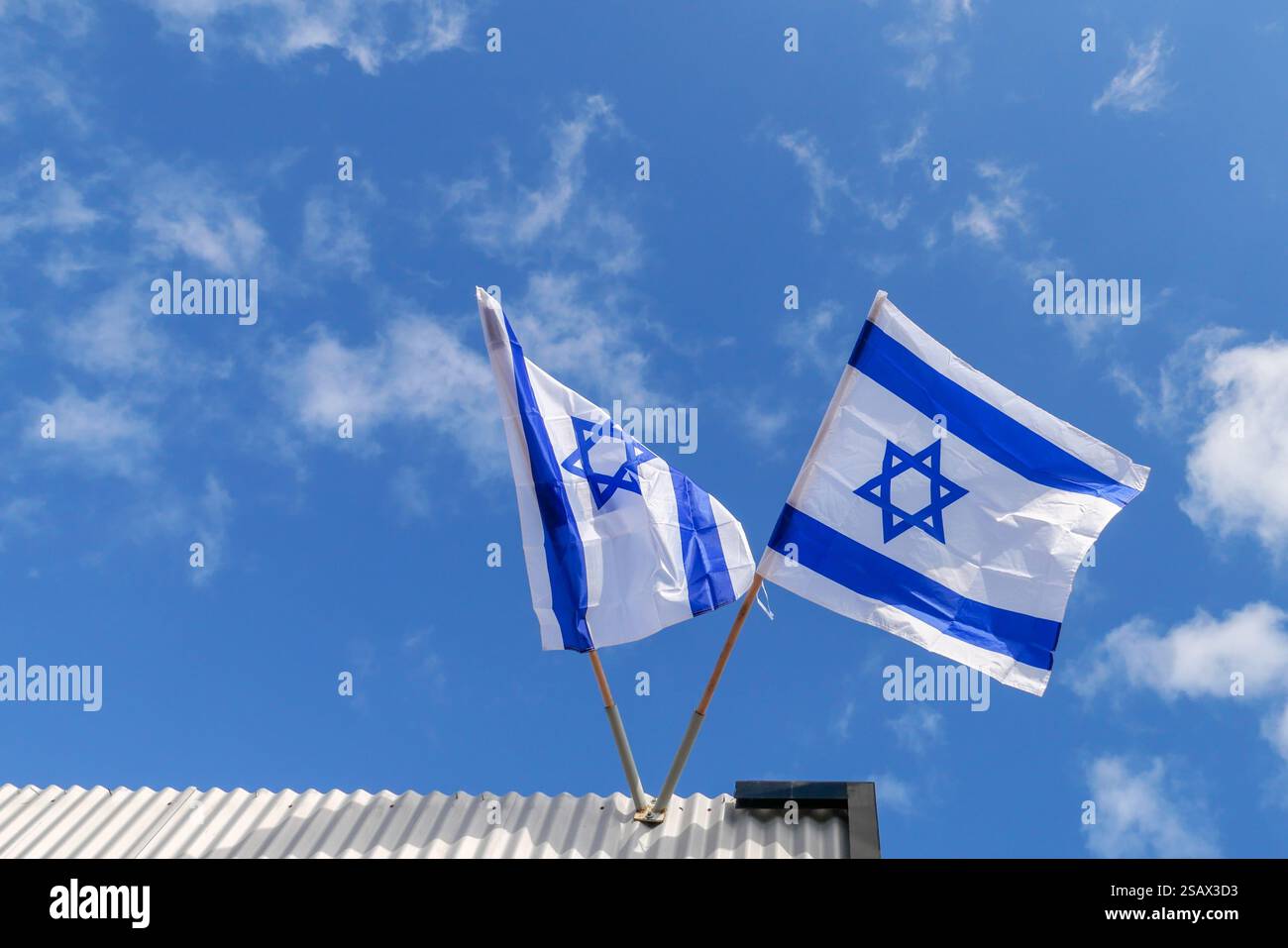Two Israeli flags flying high above a rooftop, their movement ...