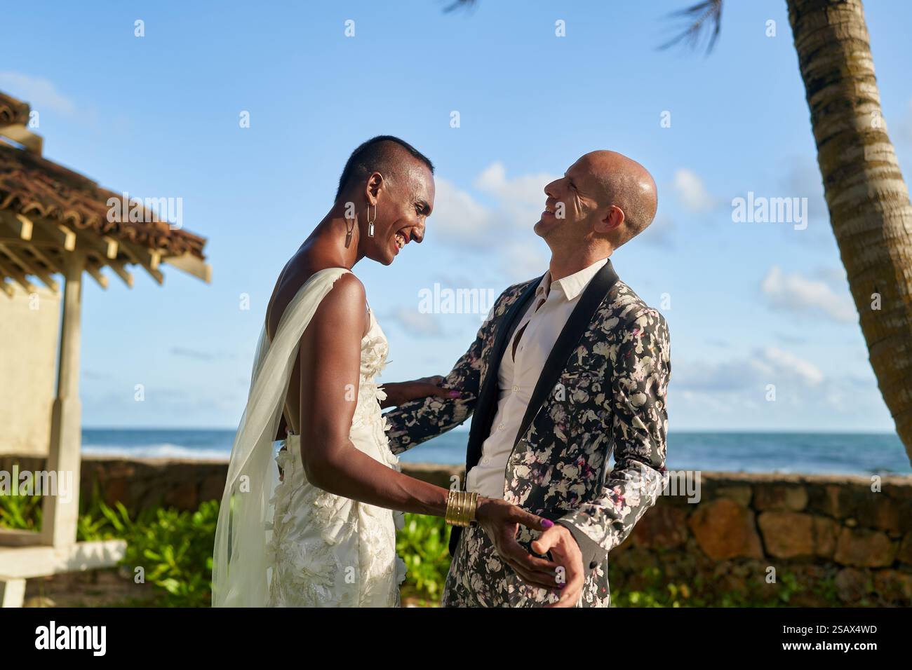 LGBTQ wedding at tropical villa. Ambiguous person in white dress as ...