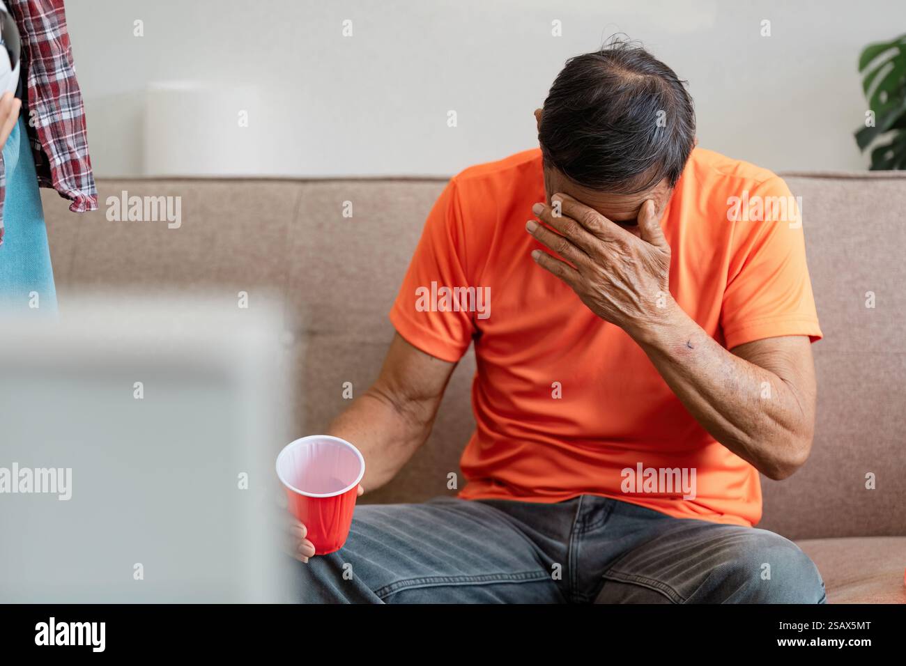 Stressed older man covering his face while watching soccer match at ...