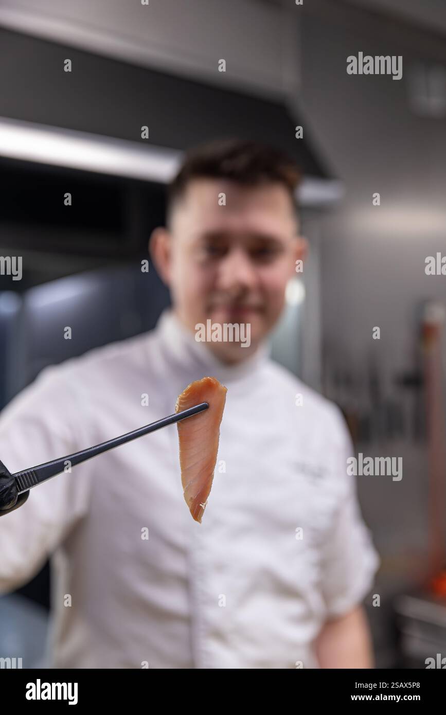 Professional chef showing a perfect slice of smoked fish, demonstrating ...