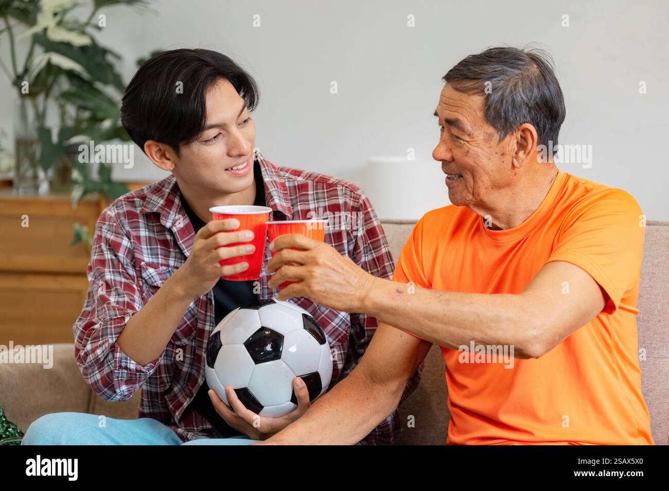Diverse family raising cups to celebrate soccer match at home Stock ...