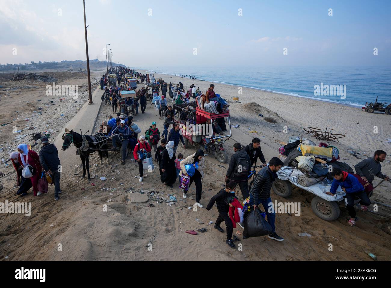 Displaced Palestinians walk on a road in central Gaza to return to ...