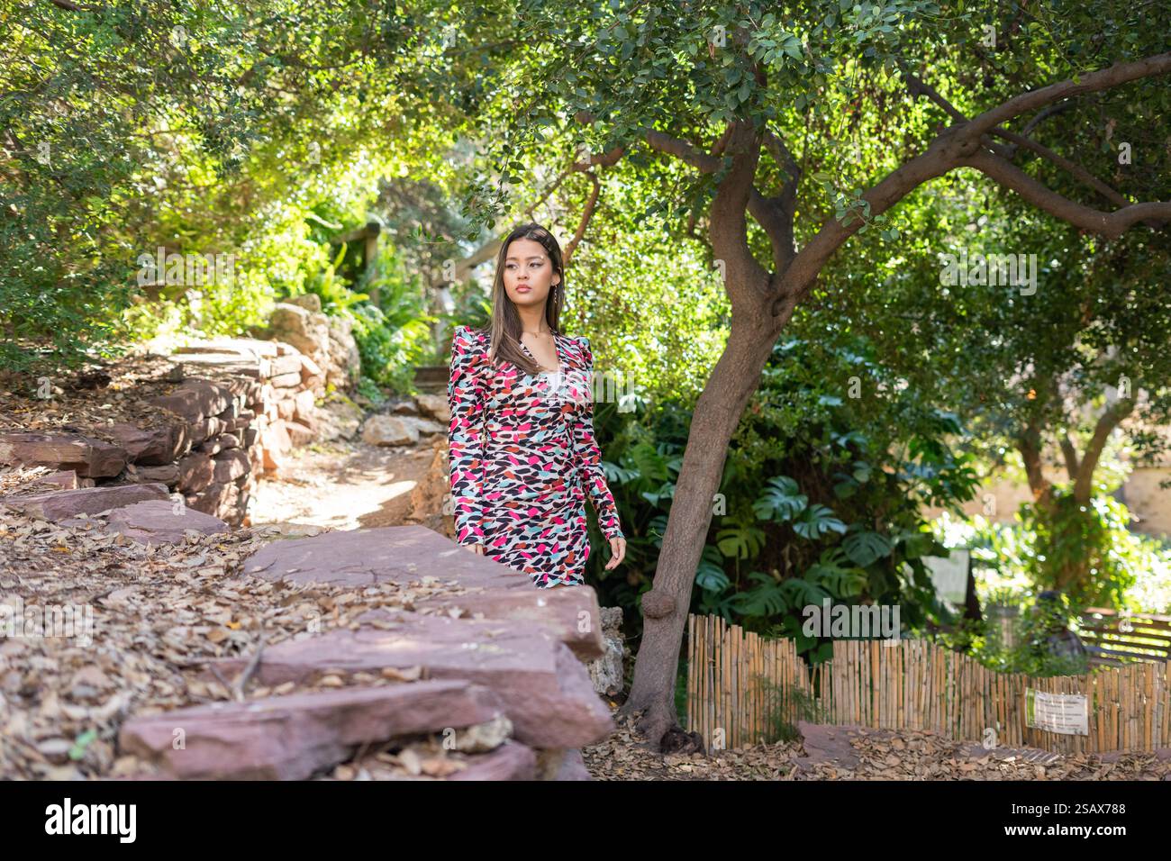 Fashion model posing in a botanical garden wearing a colorful dress ...
