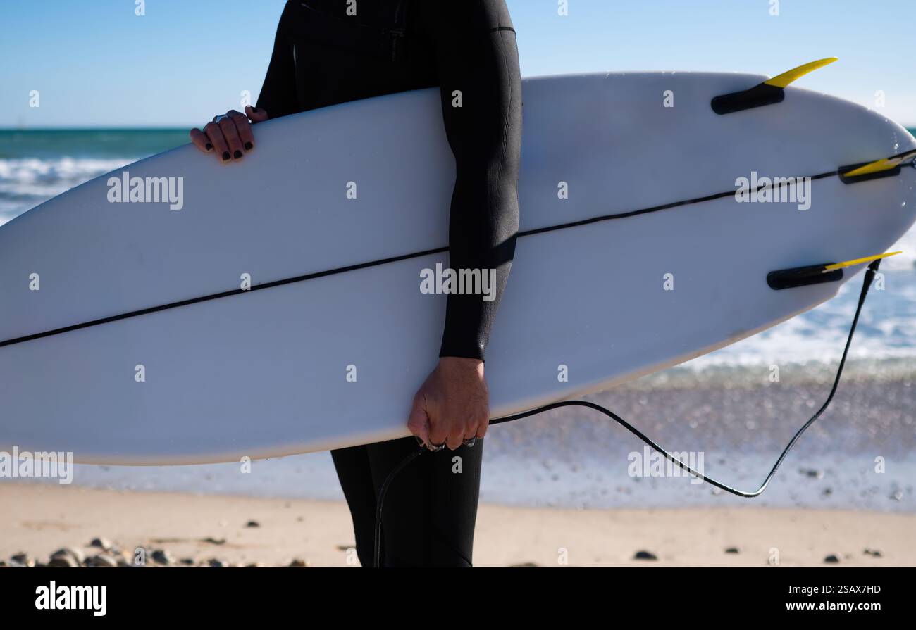 Surfer holding surfboard on sunny beach after surfing session Stock ...
