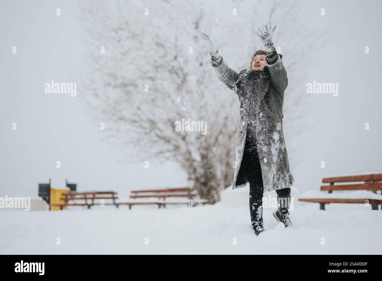 Person joyfully playing with snow in a wintery park gathering Stock ...