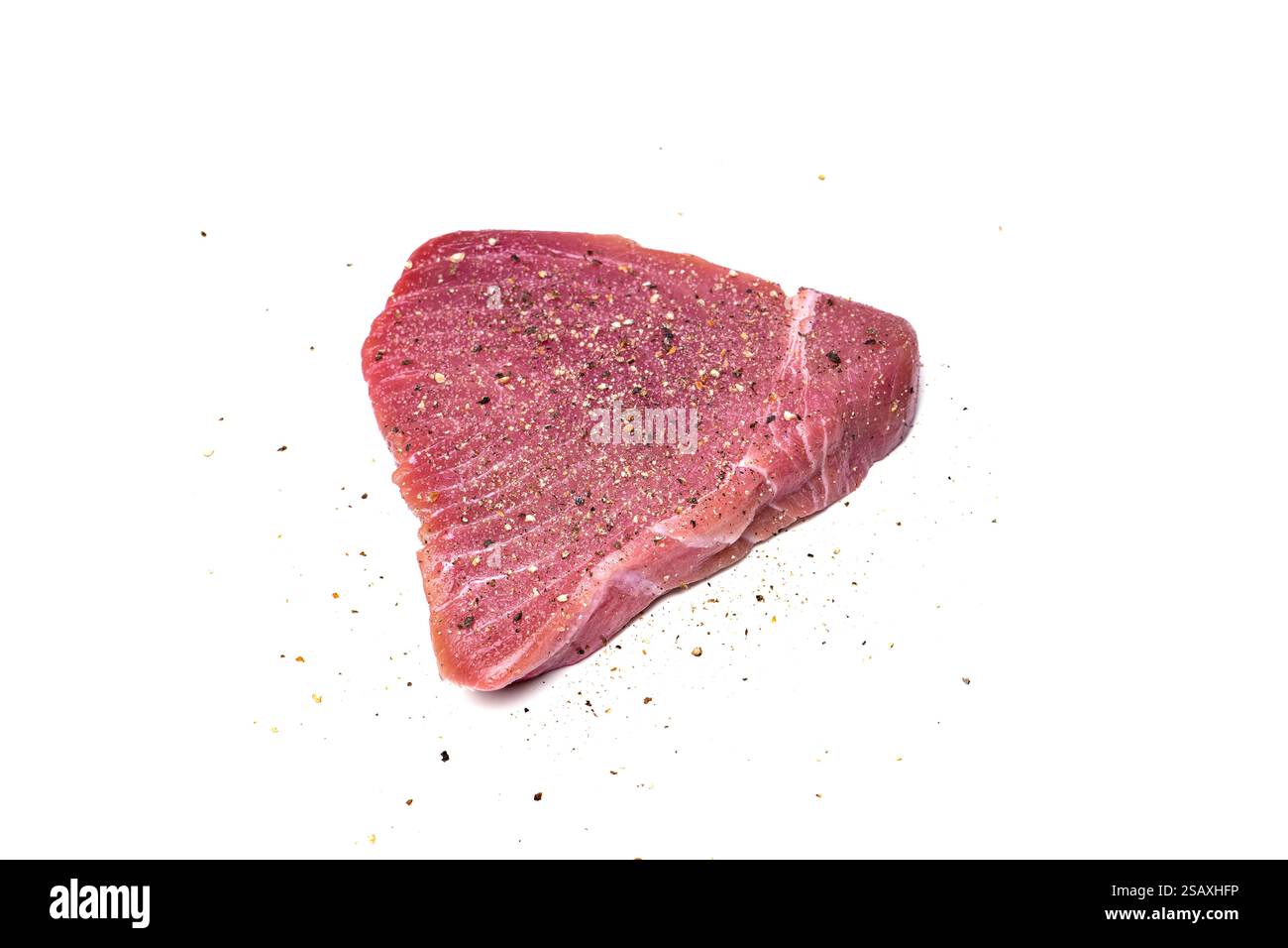 Raw, sliced, salt and coarse pepper seasoned tuna steak meat isolated ...