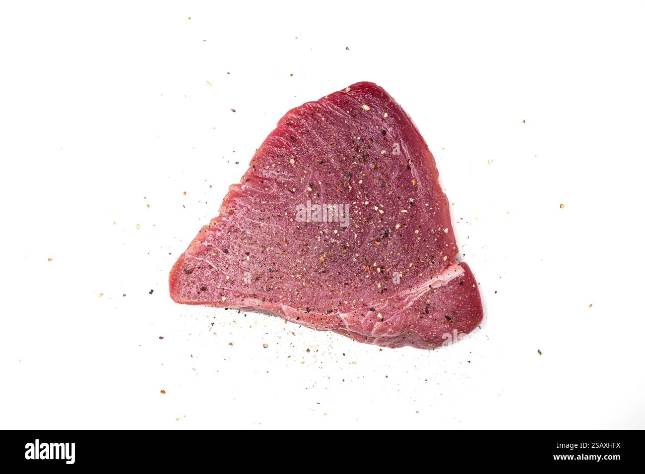 Raw, sliced, salt and coarse pepper seasoned tuna steak meat isolated ...
