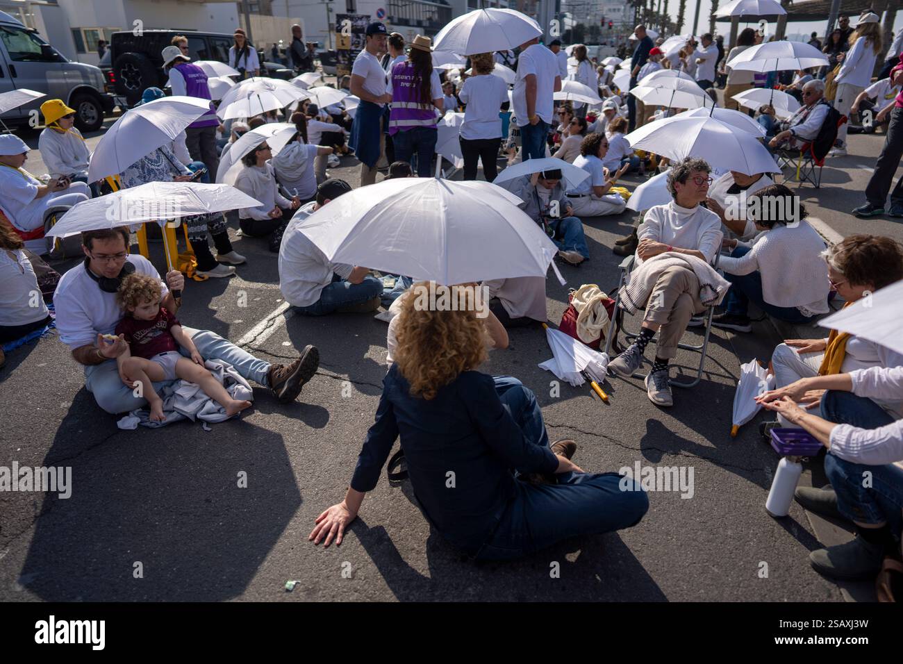 Activists sit on a road with white umbrellas during a protest calling ...