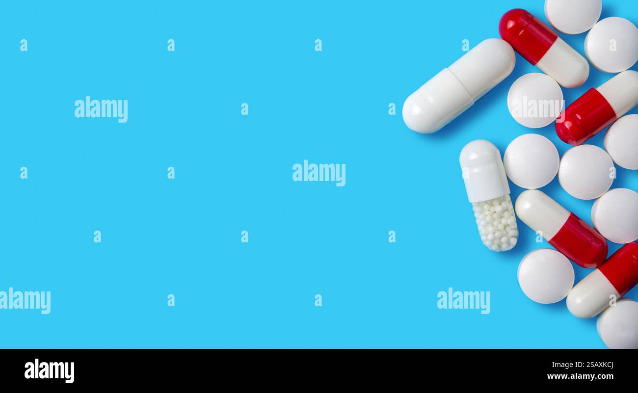 Different shapes and colors of capsules and tablets are spread across a ...