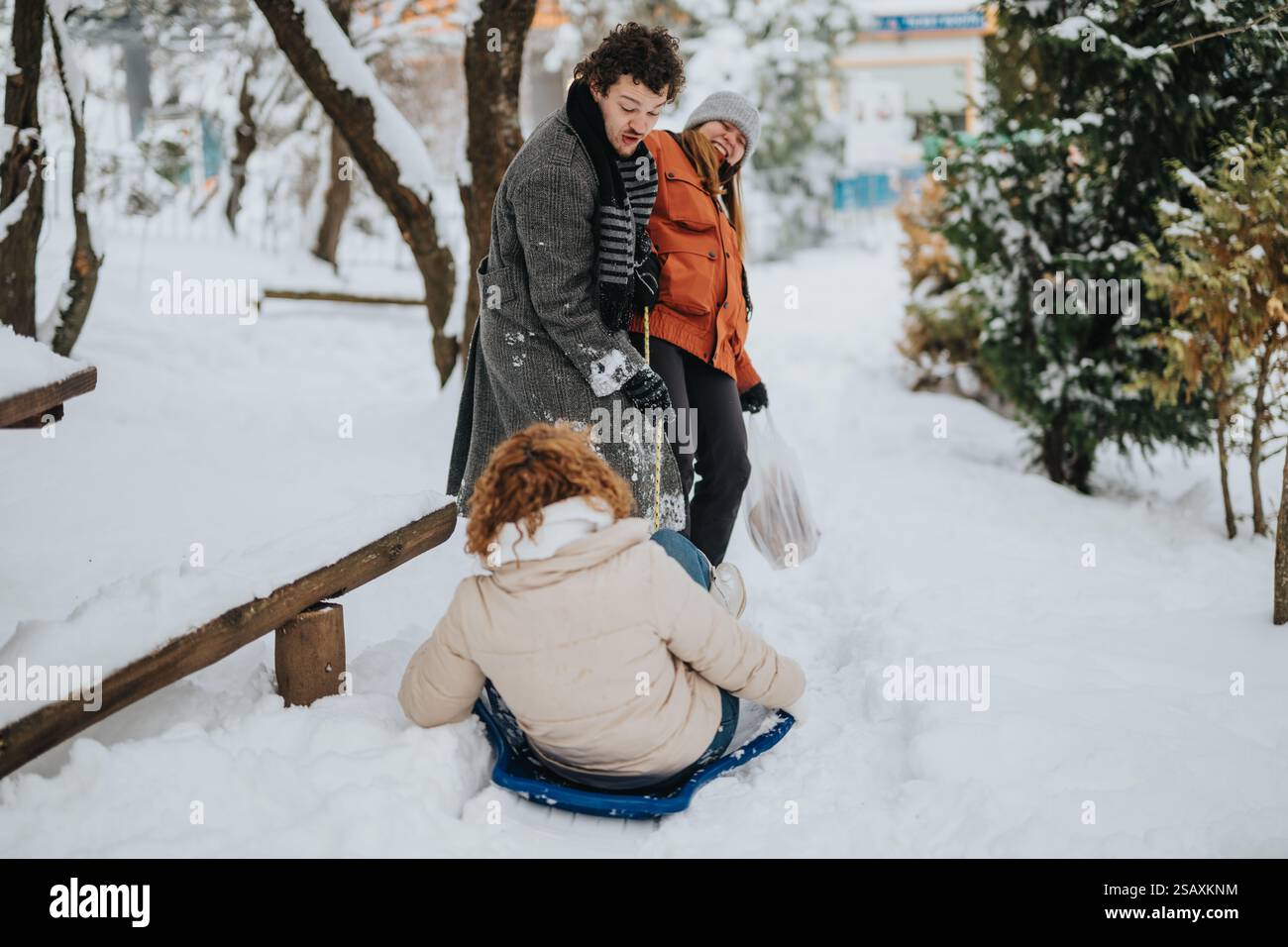 Friends enjoying a snowy day outdoors while playing and sledding ...