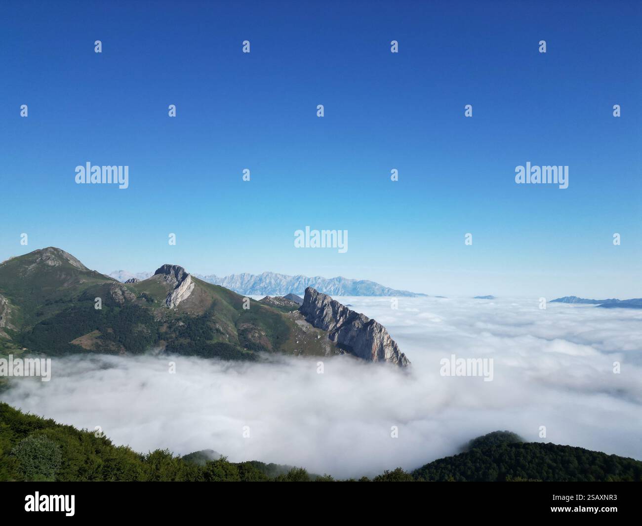 Stunning vista of mountain peaks rising above a thick blanket of clouds ...