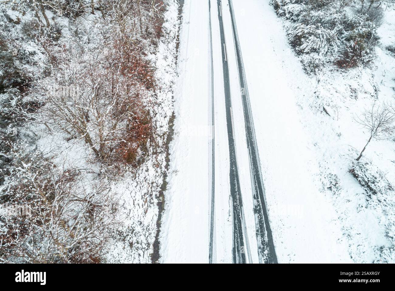aerial drone view of a road after a snowfall with tyre marks in the ...