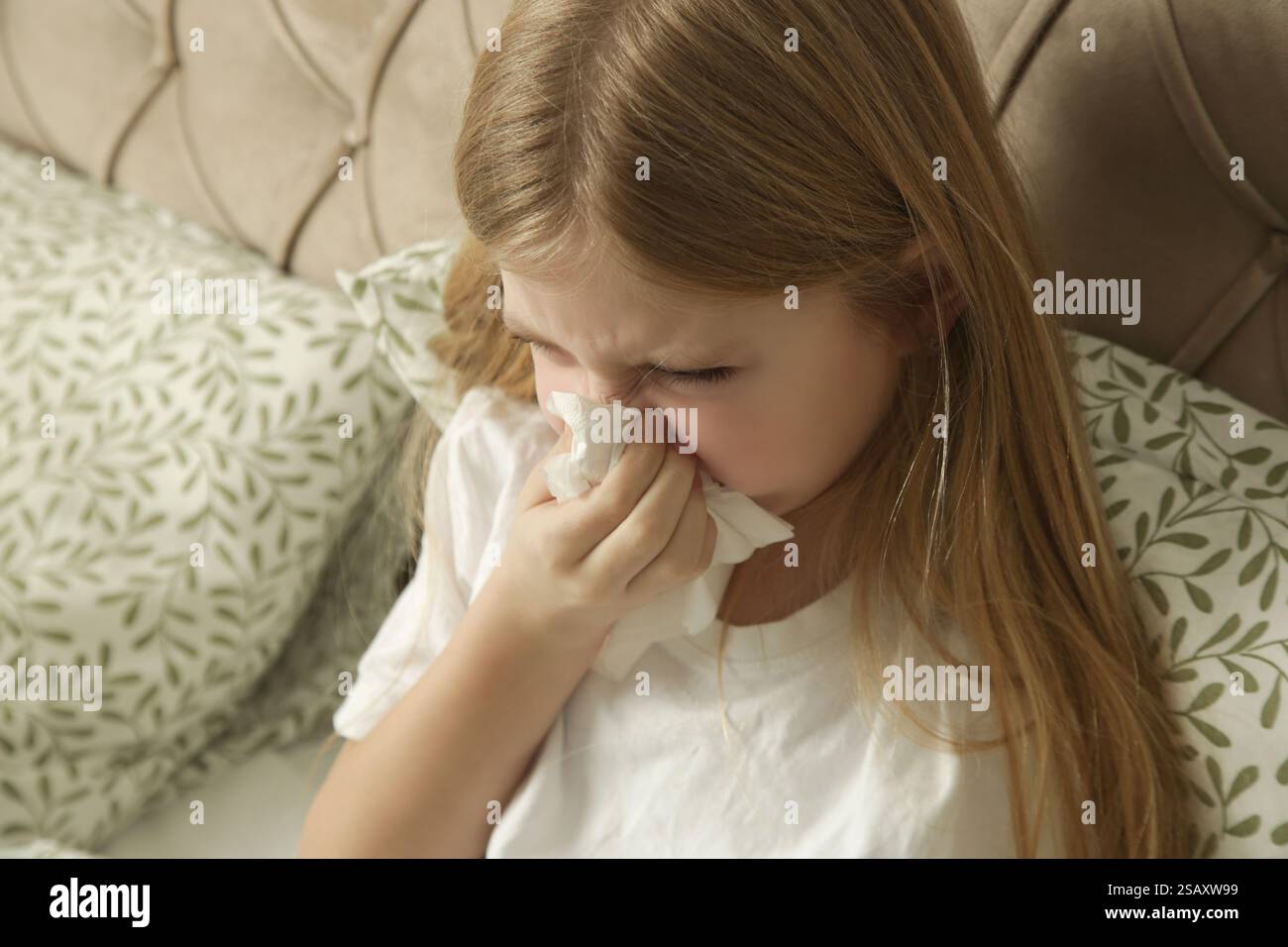 Little 7 year old girl with influenza is sitting in bed and blowing her ...