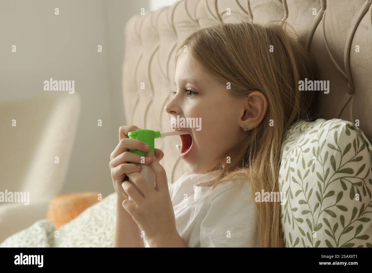 Little 7 year old girl sprays an aerosol into her mouth to treat sore ...