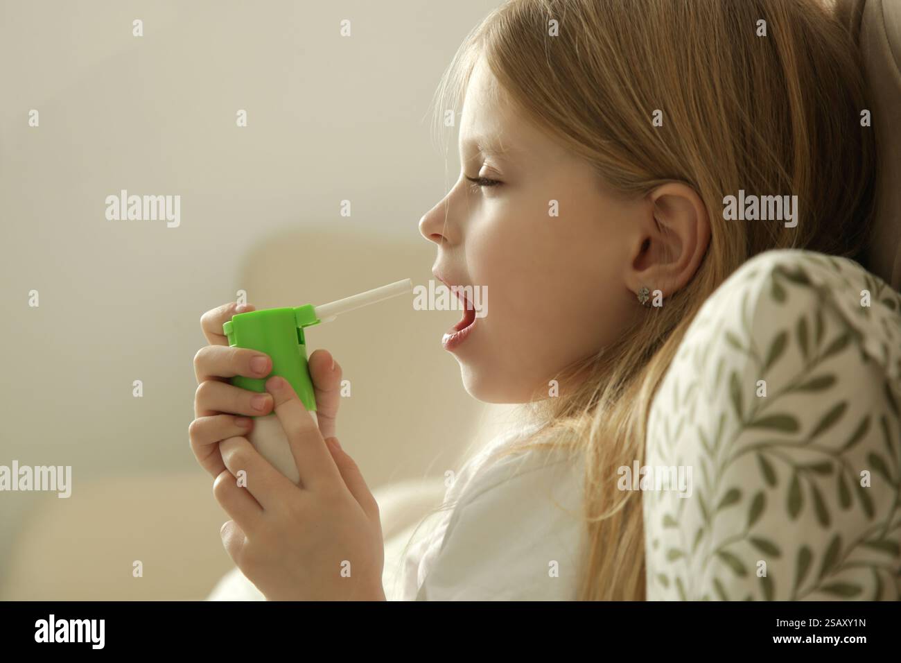 Little 7 year old girl sprays an aerosol into her mouth to treat sore ...