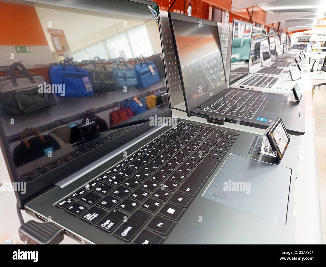 Row of laptops displayed in electronics store with reflections on ...