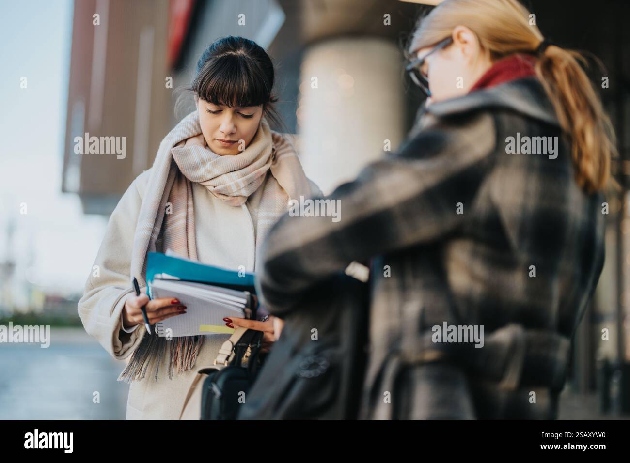 Two women reviewing documents together outside in a thoughtful meeting ...