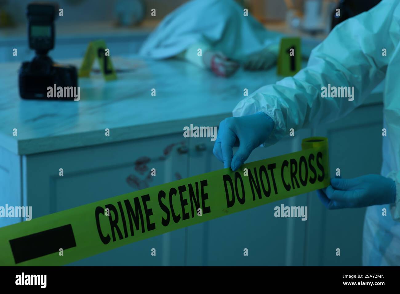 Forensic expert blocking way to crime scene with yellow tape indoors ...