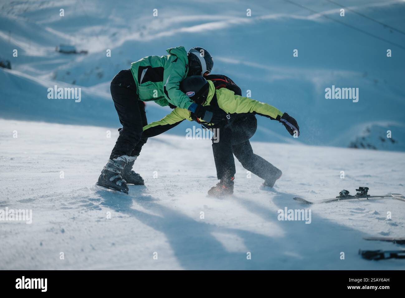 Two people helping each other on a snowy mountain terrain Stock Photo ...