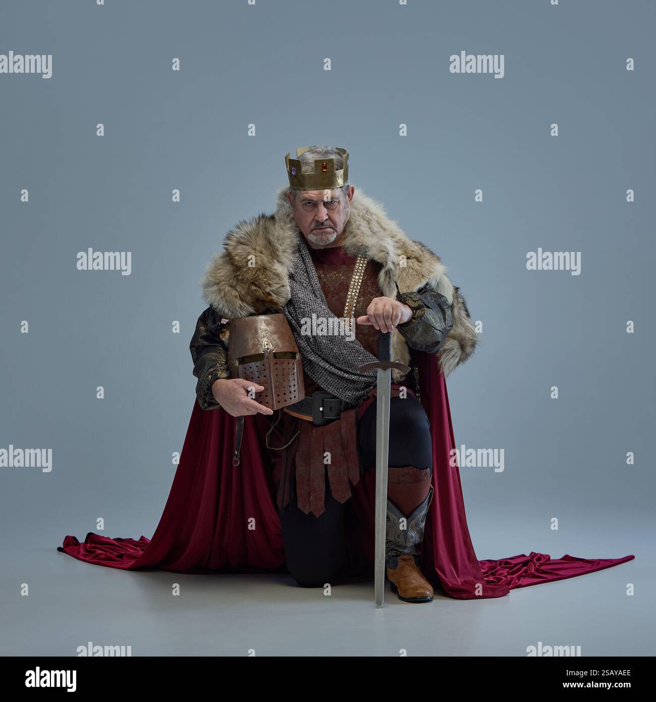 Elderly man, medieval king with crown and fur cloak holding metal ...