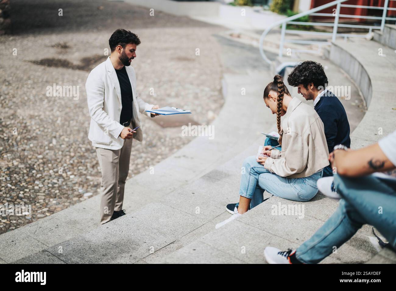 High school students receiving help from professor outdoors Stock Photo ...