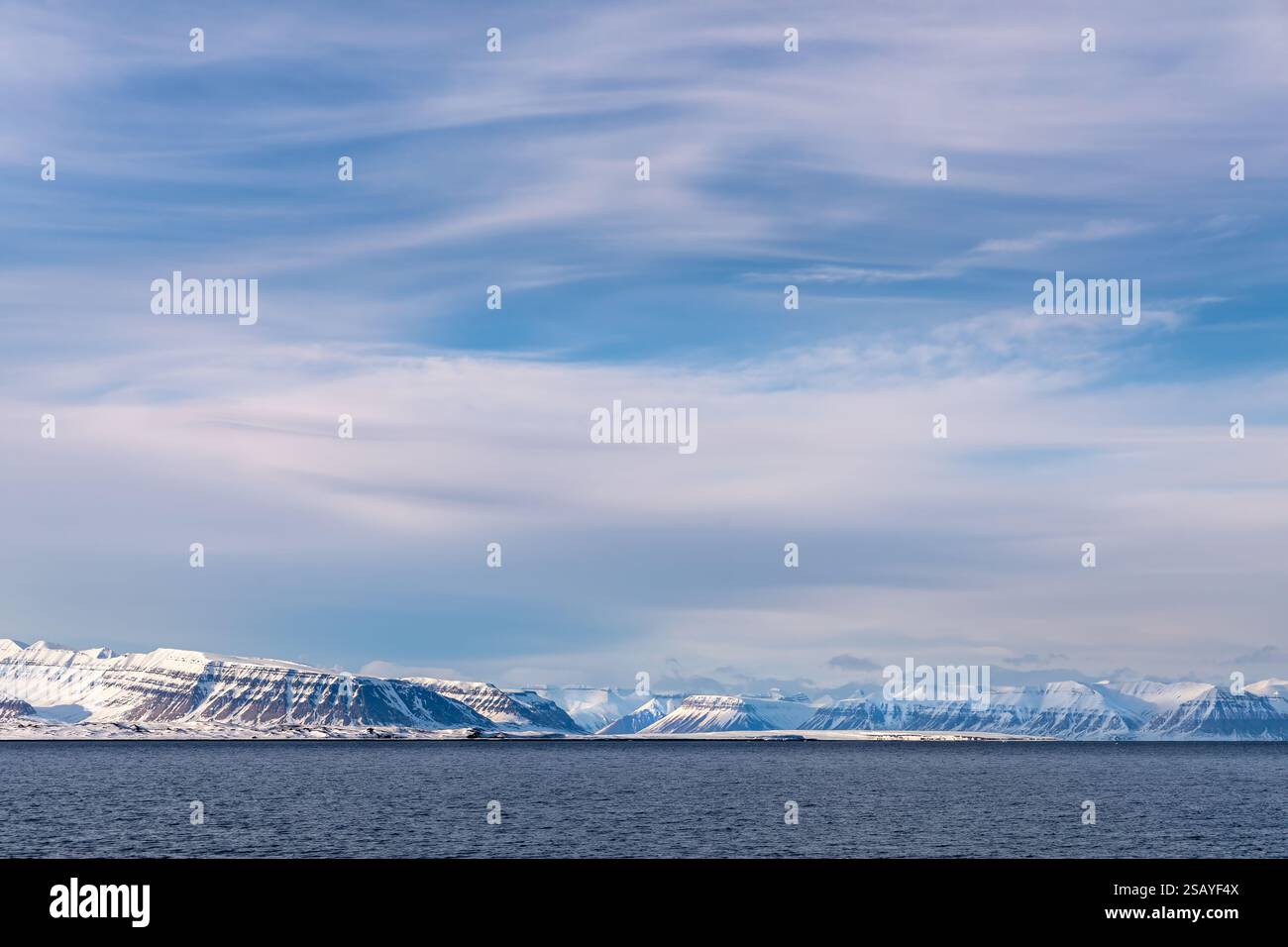 The cold blue water of the Isfjorden fjord and the sunlit mountains of ...