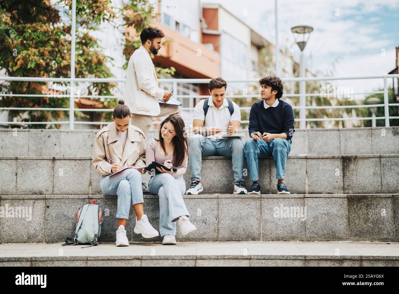 Group of students collaborating with a professor in an outdoor setting ...
