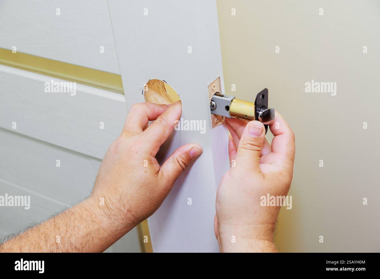 Hands installing lock cylinder into door at home during renovation ...