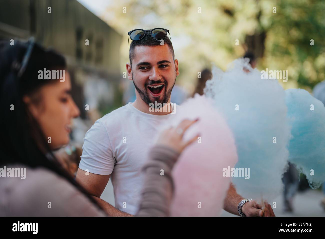 Friends enjoying cotton candy at a lively outdoor festival Stock Photo ...
