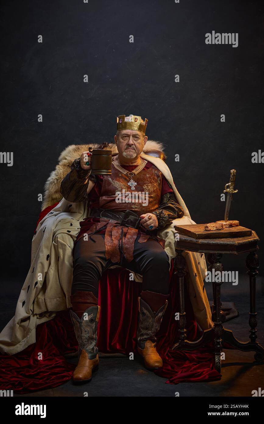 Cheers. Man as medieval king sitting on throne, raising wooden mug of ...