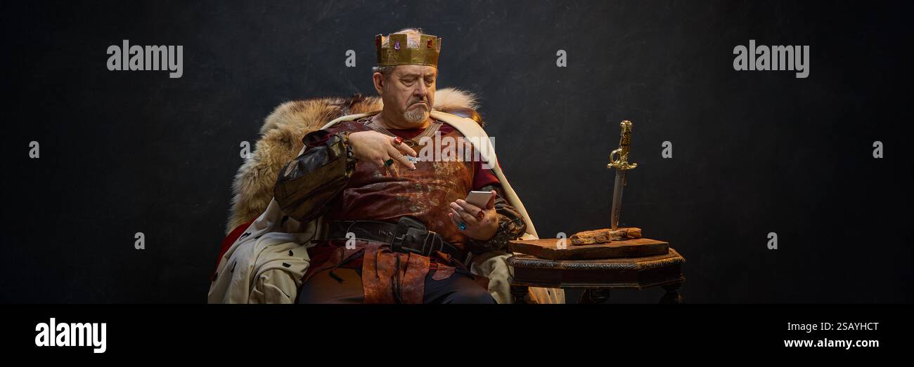 Serious man, medieval king in crown sitting on throne and looking on ...