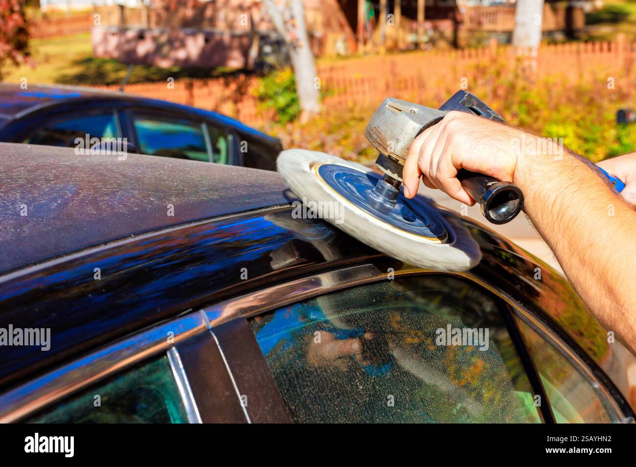 Technician worker is using buffing tool to polish top of dusty car in ...