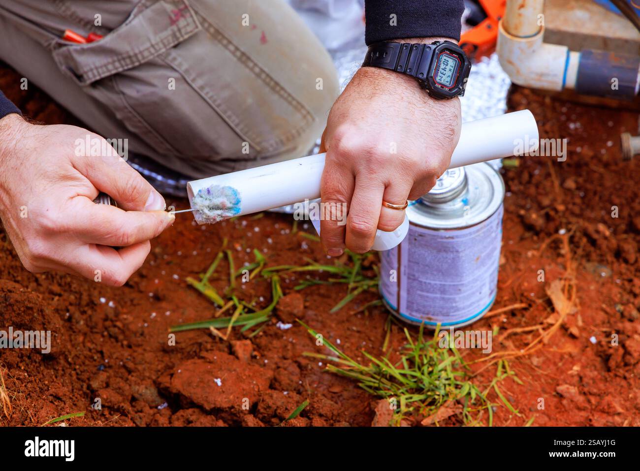 Repairing plumbing with PVC pipes, adhesive on water well system, hands ...