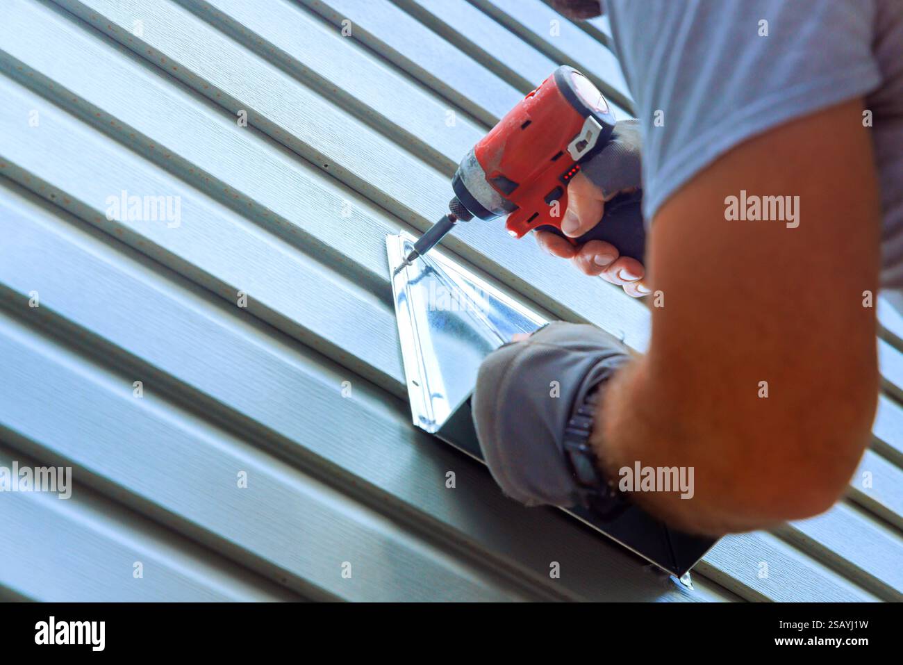 Carpenter is securing metal ventilation cover panels using power ...