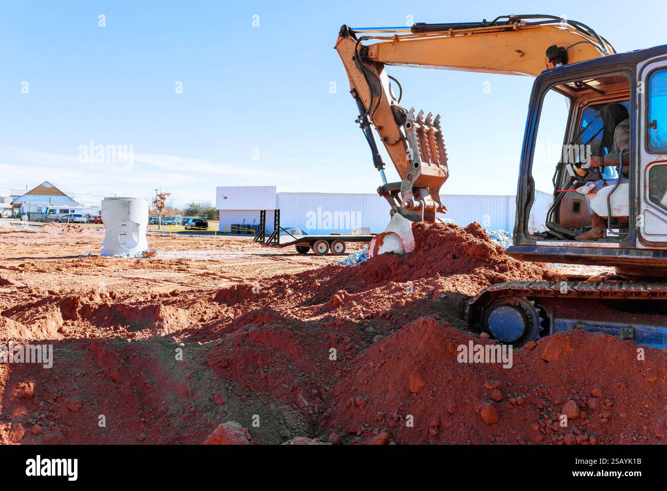 Heavy excavator action digs trench for drainage pipe at construction ...