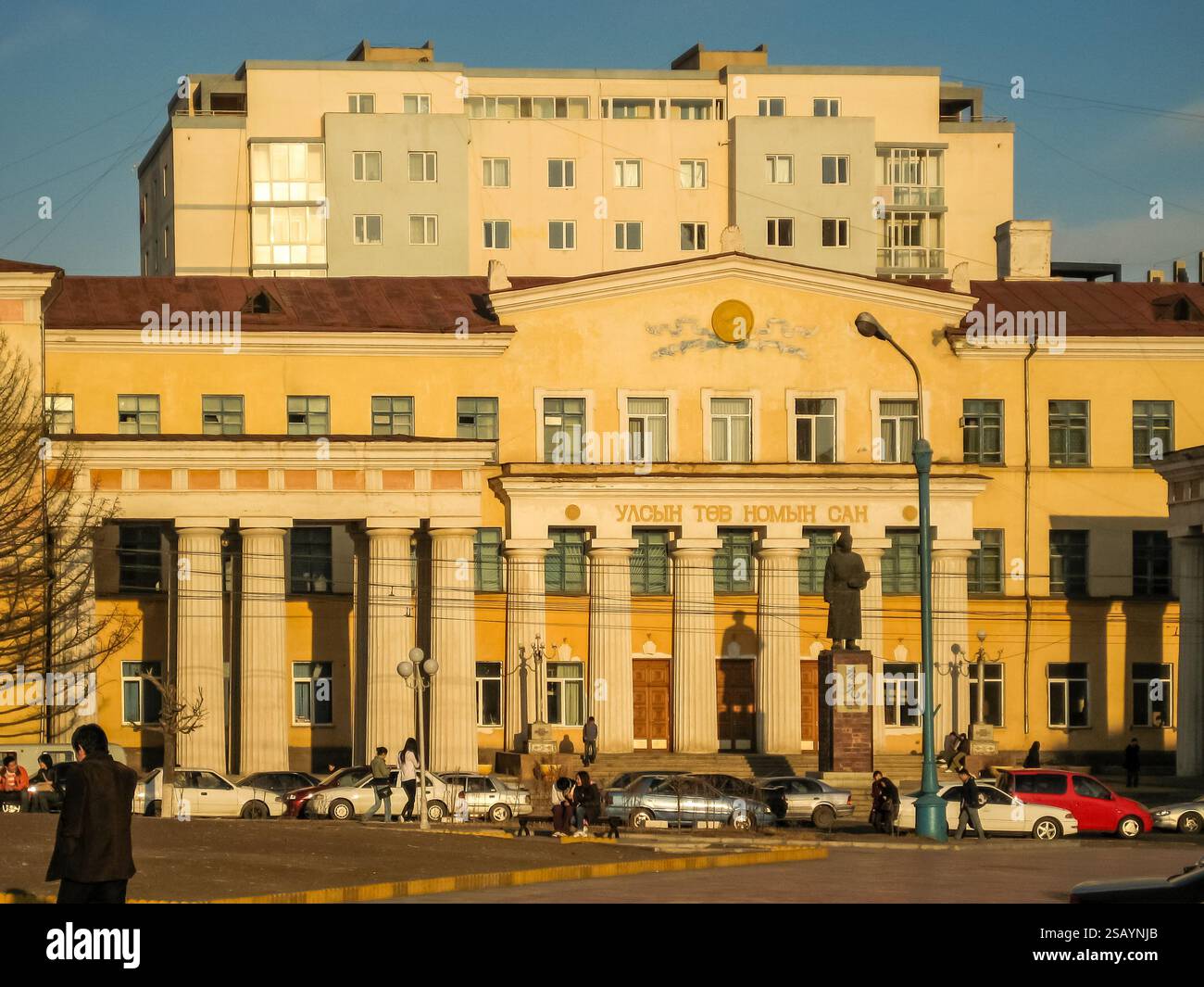 A large building with a statue of a man in front of it. The building is ...