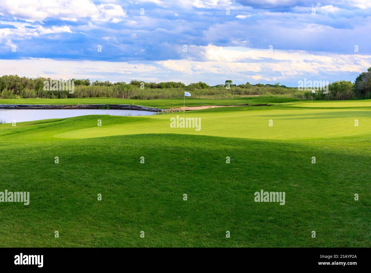 A golf course with a green grassy hill and a flag on the ground. The ...