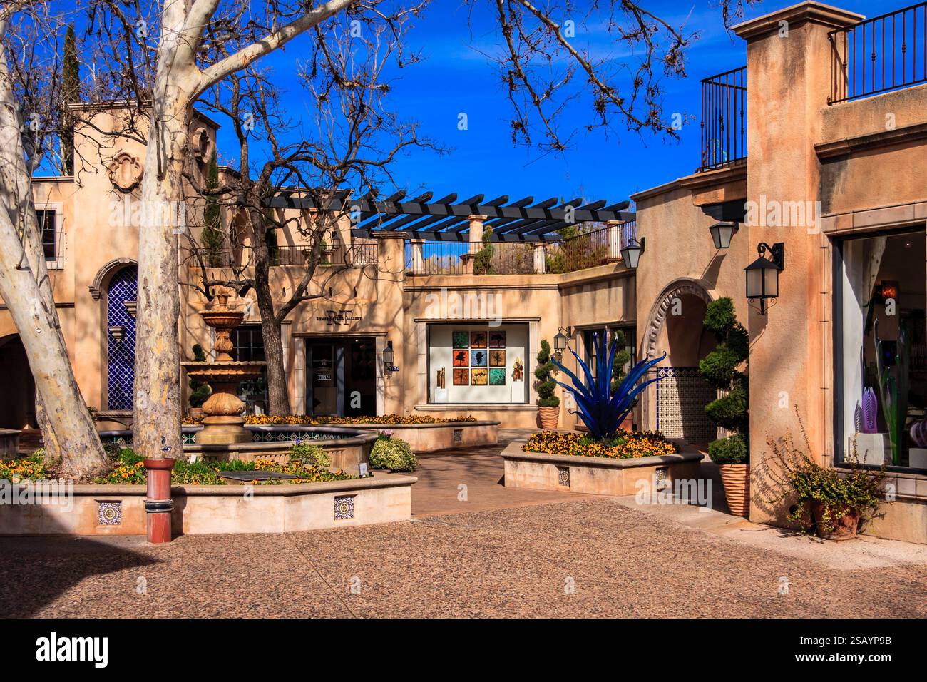 A courtyard with a fountain and a large tree. The courtyard is ...
