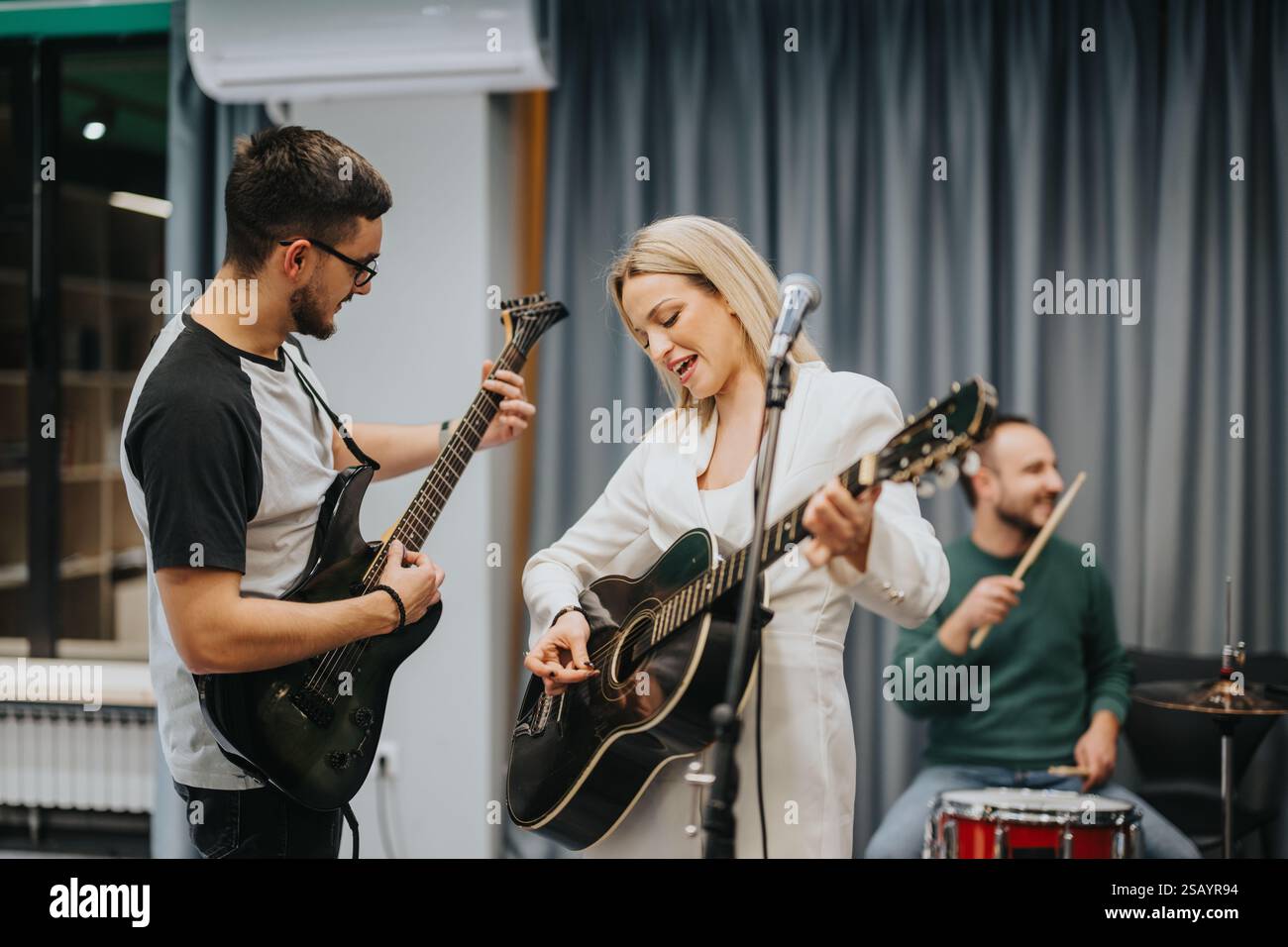 A group of musicians practicing and creating music in a band rehearsal ...