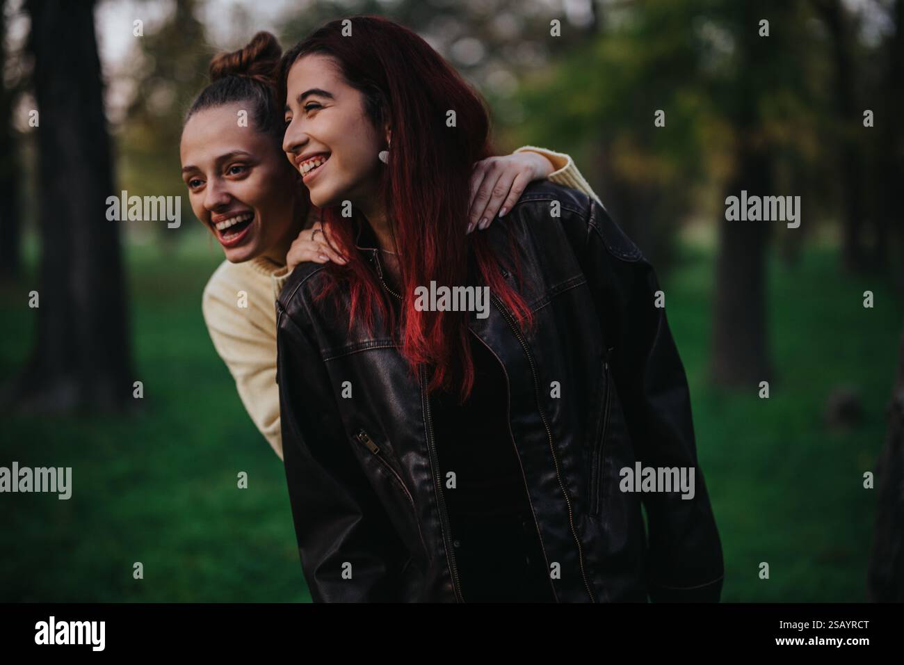 Two friends laughing together outdoors in a green forested area Stock ...