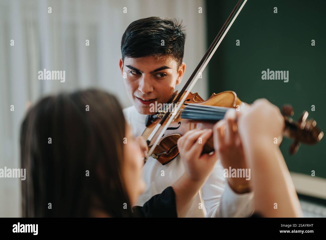 Young violinist learning to play while receiving guidance from a ...