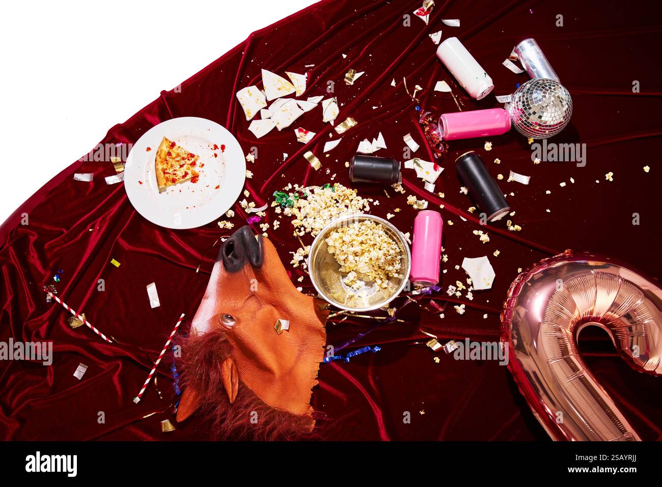 Spilled popcorn, broken plates, empty pizza box, and horse mask on red ...