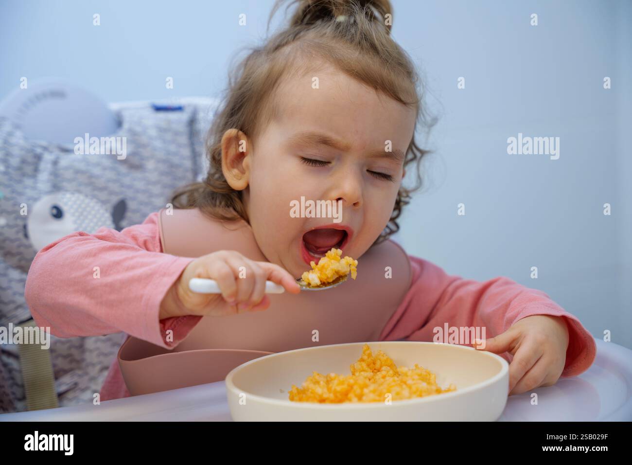 Toddler eating rice with tomato sauce, promoting healthy child ...