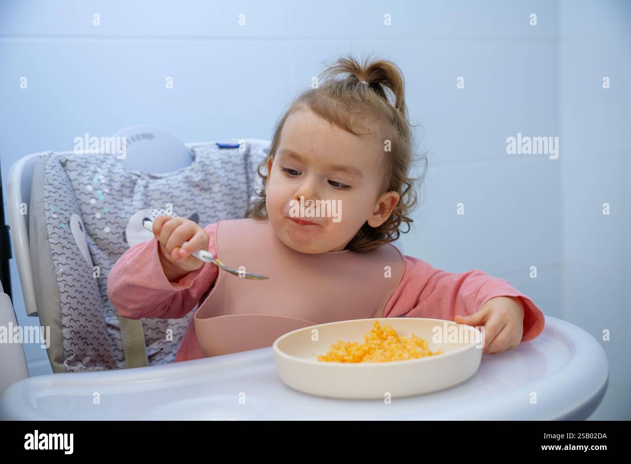Toddler eating rice with tomato sauce, promoting healthy child ...