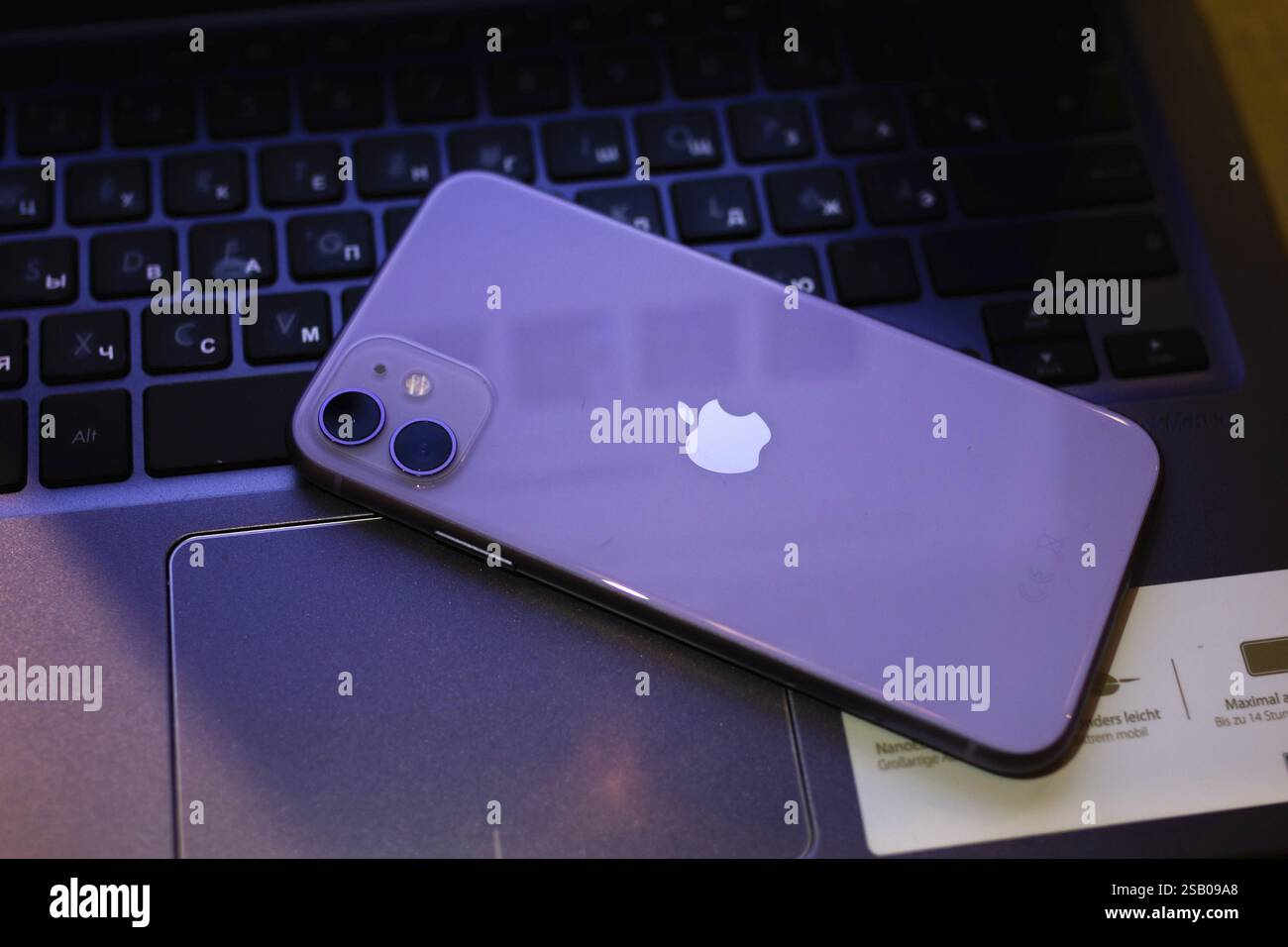 An upside-down iPhone rests on a laptop keyboard, featuring a visible ...