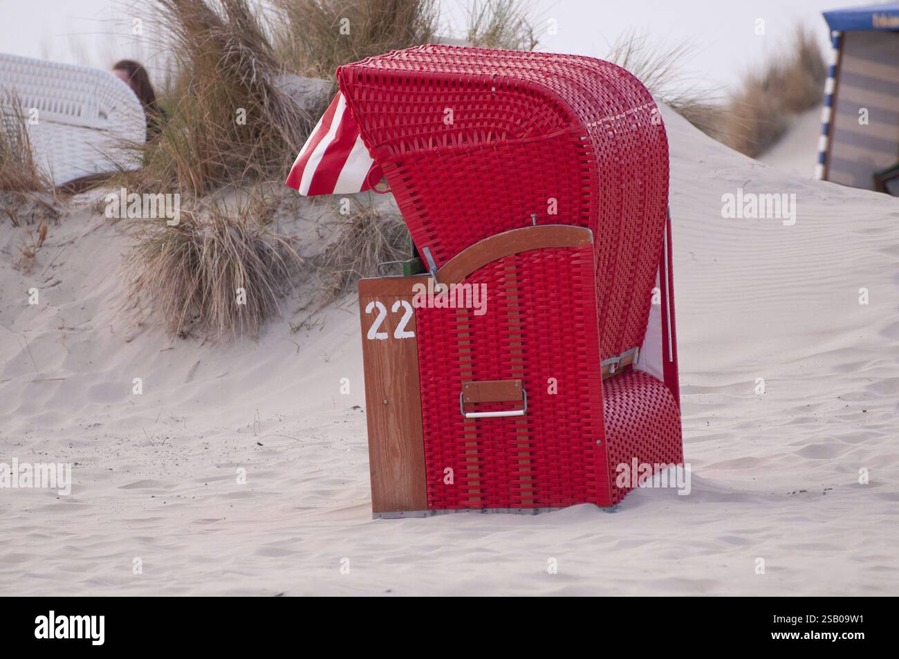Red beach chair standing in the sand next to dunes, Borkum, north sea ...