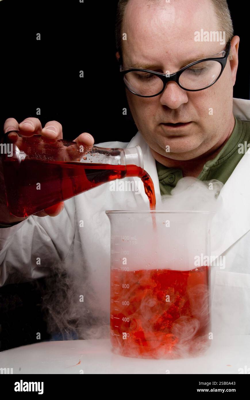 A Scientist pouring a solution into a beaker Stock Photo - Alamy