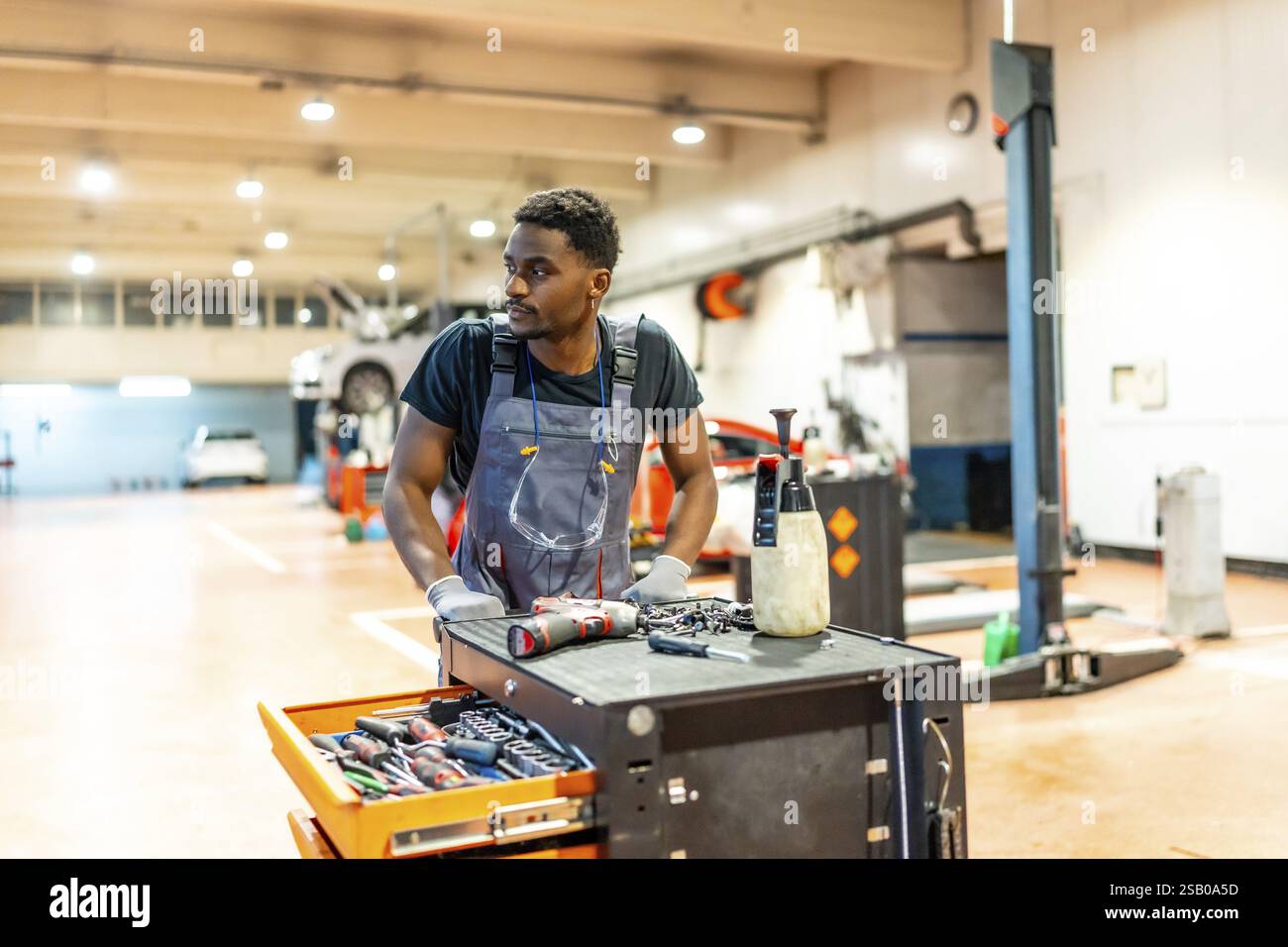 Young mechanic working on a car in a professional garage, using tools ...
