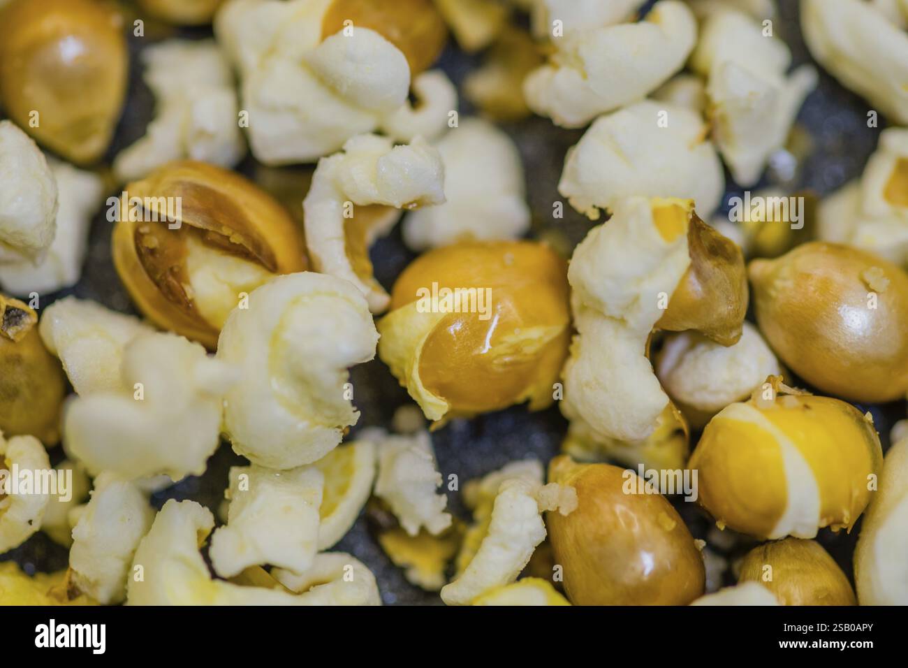 Close-up of popcorn with unpopped kernels scattered across the surface ...