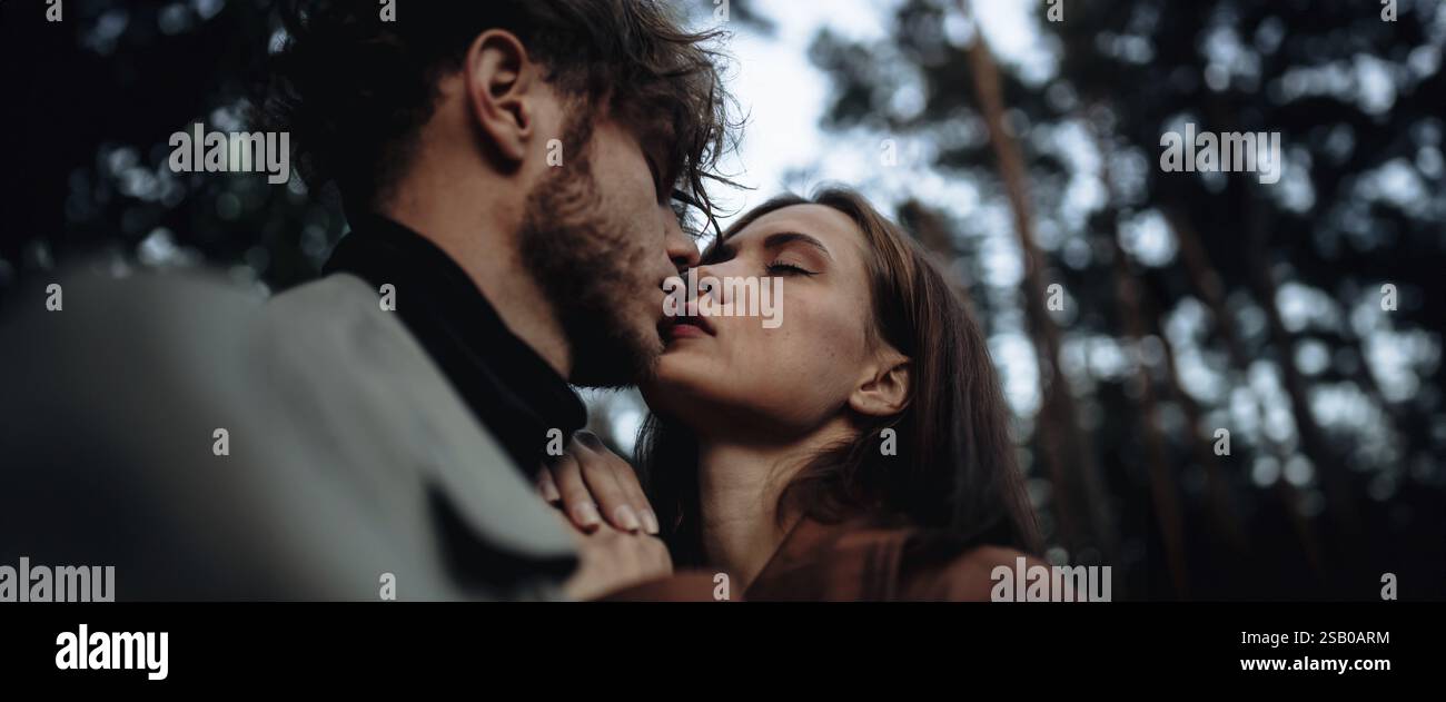 An intimate moment between a couple about to kiss at dusk in a forest ...